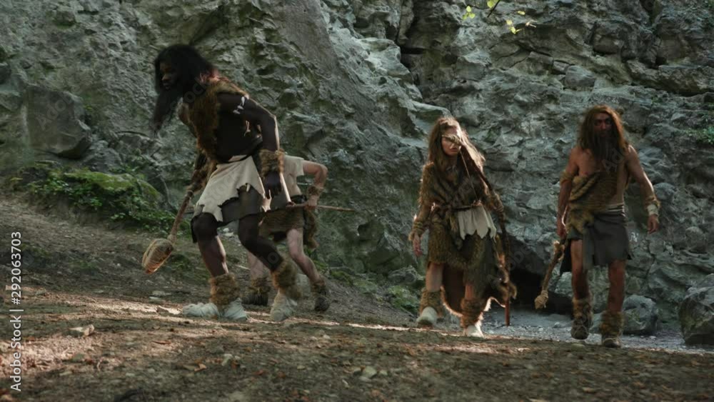 Primitive tribe of wary neanderthals walking slowly in prehistoric ...