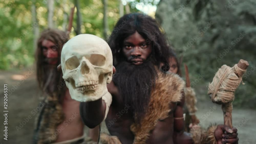 Prehistoric wild tribe of neanderthal cannibalists showing human skull ...