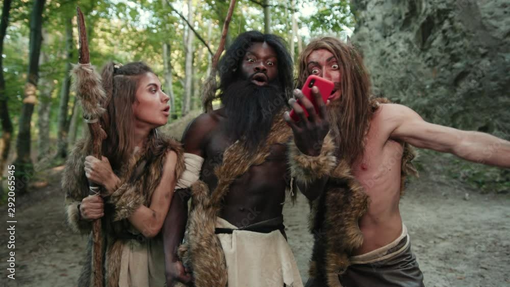 Cheerful group of neanderthal hunters using modern technology ...