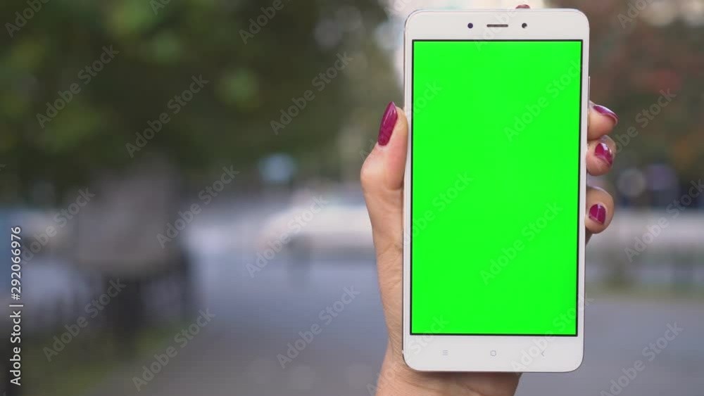 Female hand holding smartphone with green screen. Girl using mobile ...