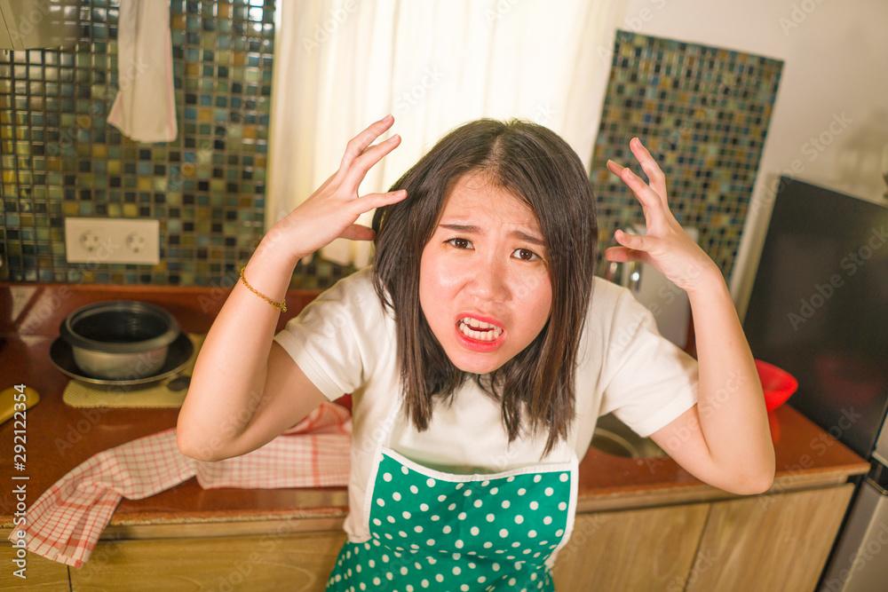 young tired and stressed Asian Chinese woman in cook apron working in ...