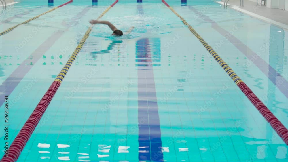 Professional swimmer in indoor pool swimming across track. Healthy ...