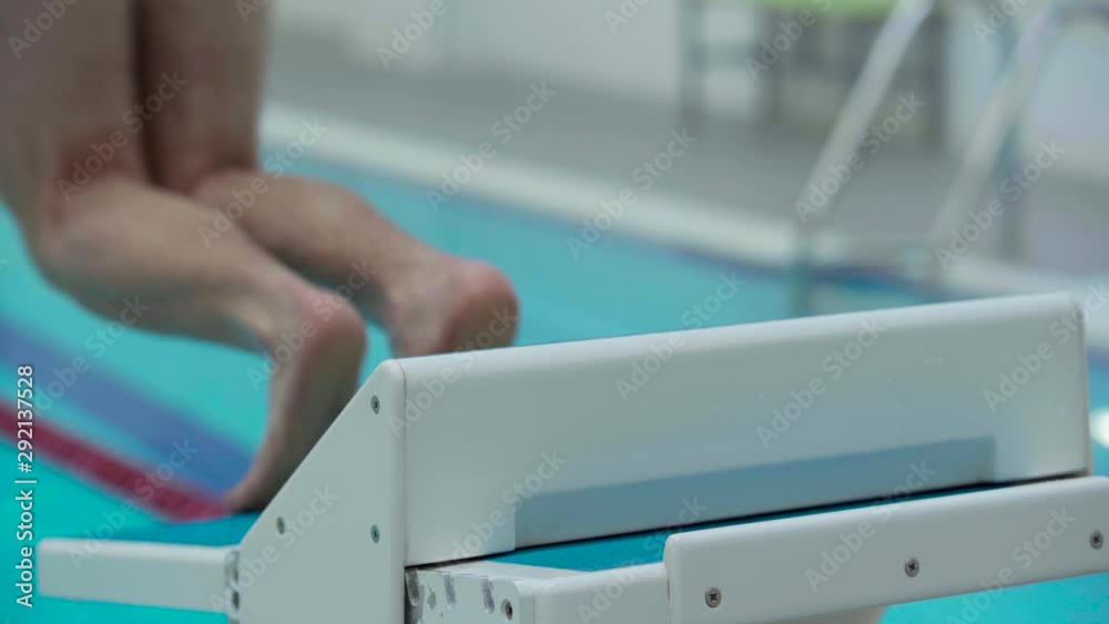 Professional sporty male swimmer jumping off into the swimming pool ...
