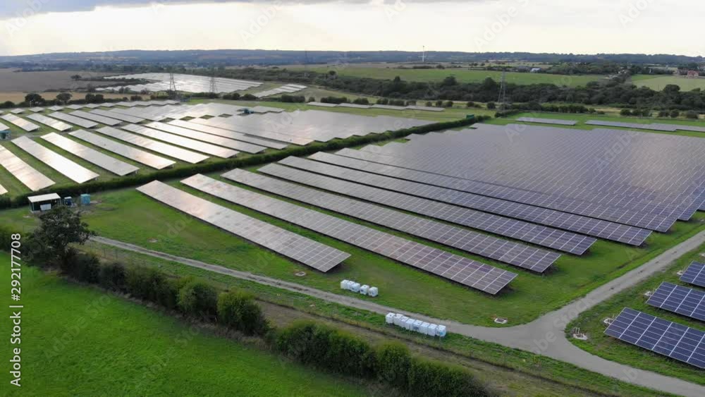 Aerial view of a solar farm with sunrays reflecting on the solar panels ...