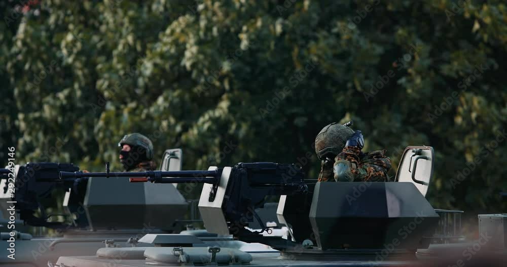 Military man with a gun sitting on an armored car. War vehicle in ...