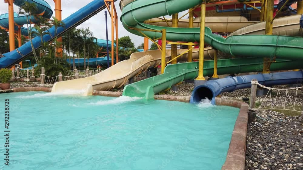 Colorful Water slides at the water park, water flowing in to the ...