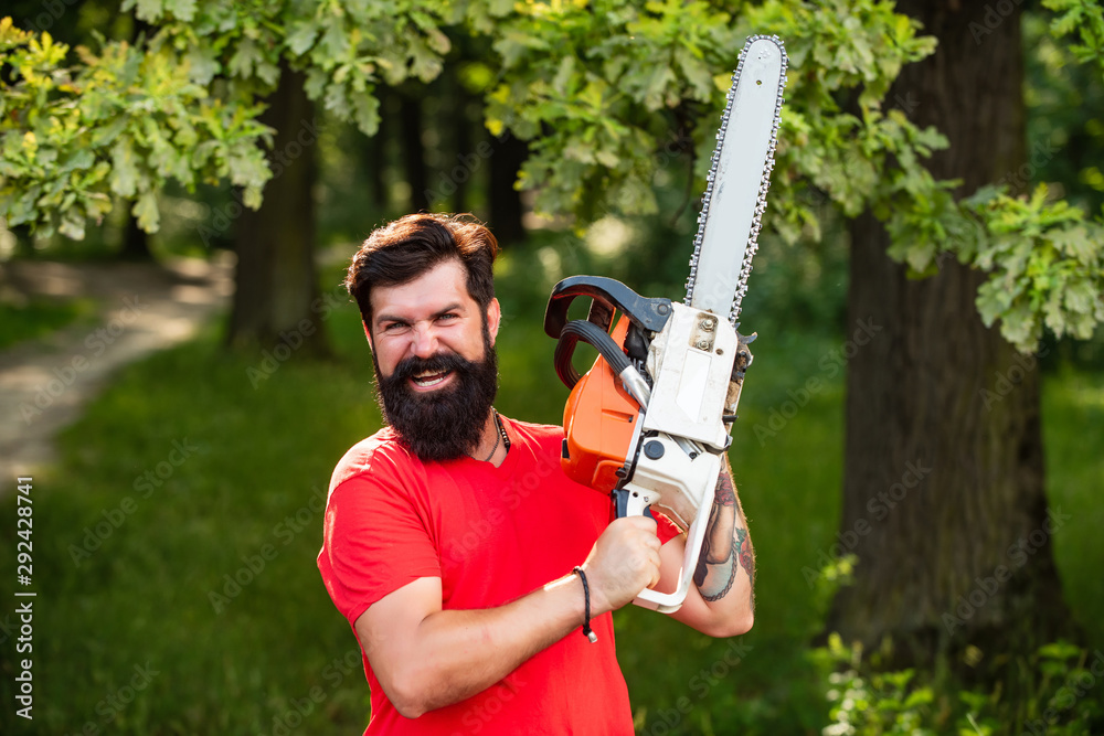 Lumberjack with chainsaw on forest background. Lumberjack holding the ...