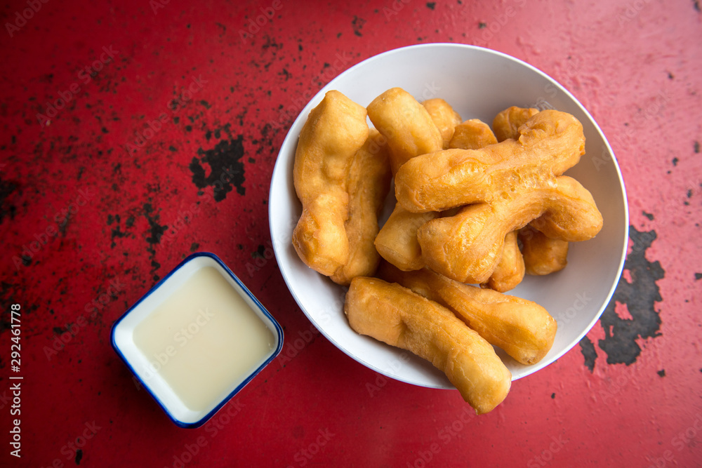 Patongo (or Chinese Doughnut)with condensed milk on the red table. This ...