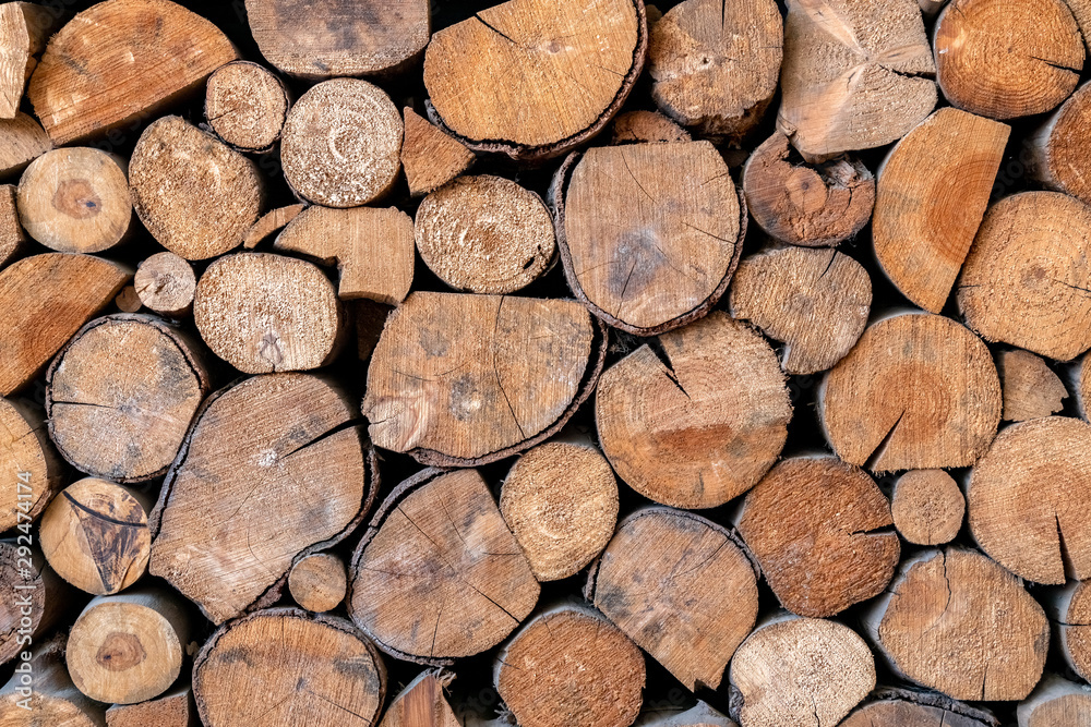 Pile of wooden logs stacked together on top of each other. Wall of ...