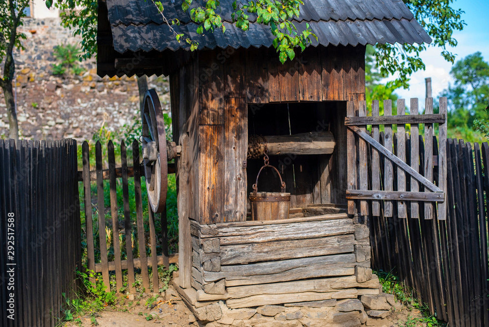An old wooden well with a wooden bucket that once used to draw water ...