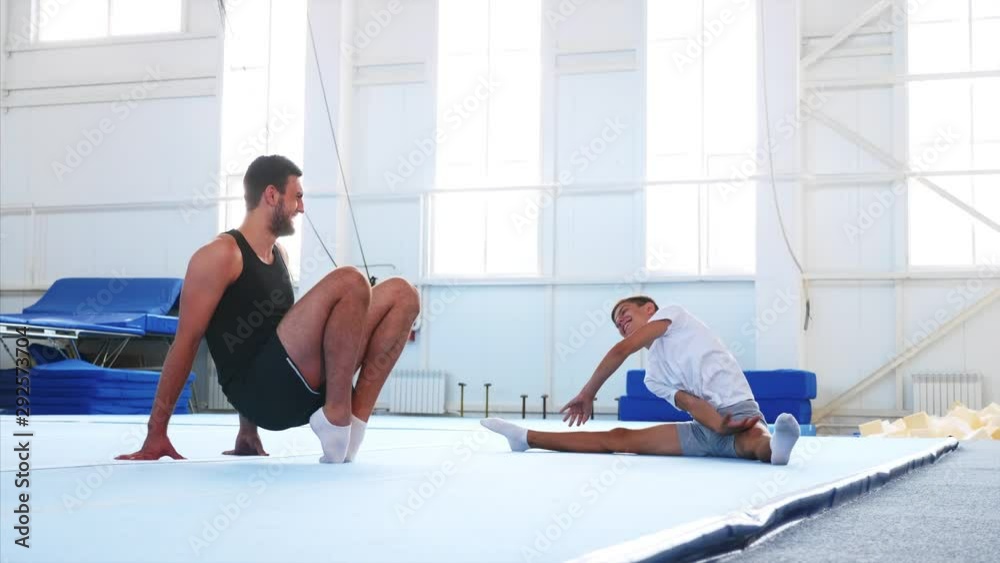 Vidéo Stock A man athlete is stretching his feet over and teenager ...