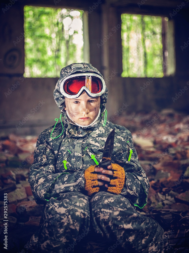 Serious girl in military uniform with knife in her hands sits near a ...