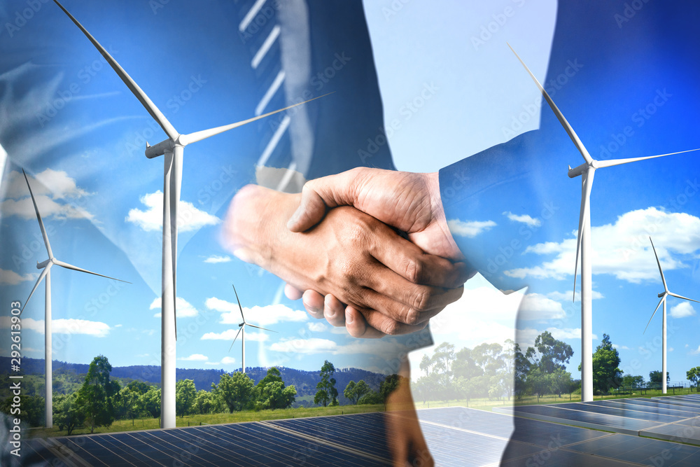 Double exposure graphic of business people handshake over wind turbine ...