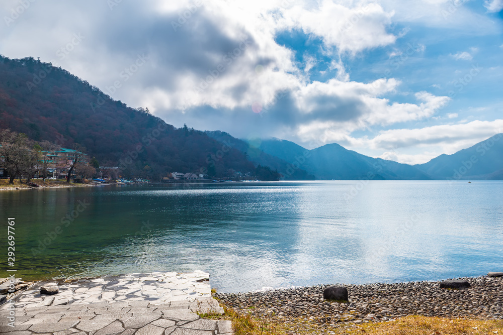 beautiful day scene of lake Chuzenji with houses, trees and mountains ...