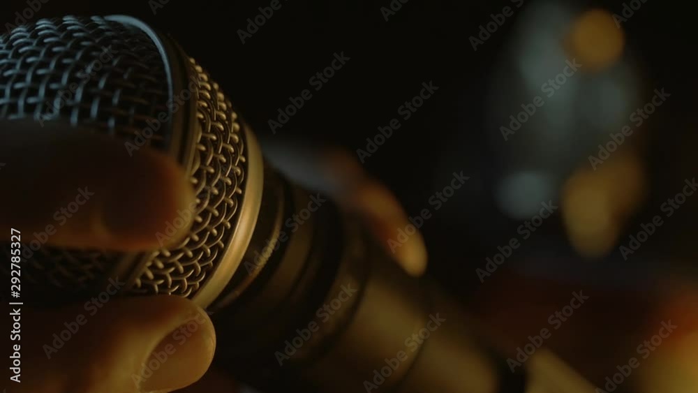 A hand is putting together a dynamic microphone in a half-light ...