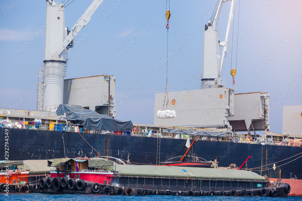 Loading goods on cargo ship with crane. Shipment from a merchant to a ...