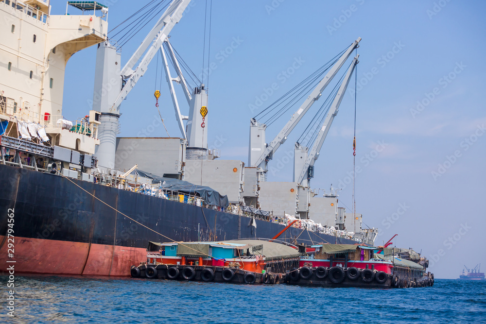 Loading goods on cargo ship with crane. Shipment from a merchant to a ...