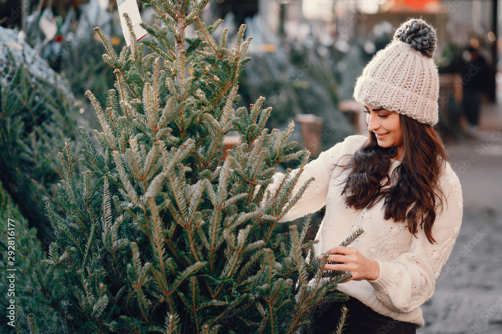 Elegant girl buys a Christmas tree. Woman in a white knited sweater ...