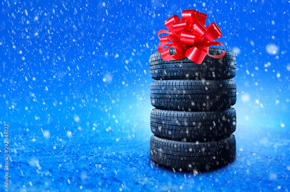 New winter tires pile as a gift. Tyres pile with a big red bow, as a ...