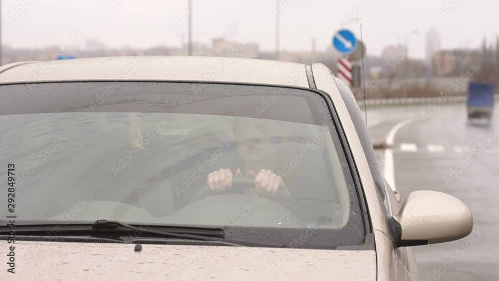 View through the windshield of the car on the girl, she sits in the car ...