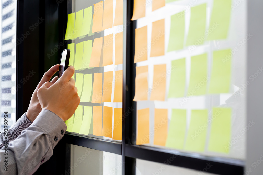 IT worker tracking his tasks on kanban board in mobile phone ...