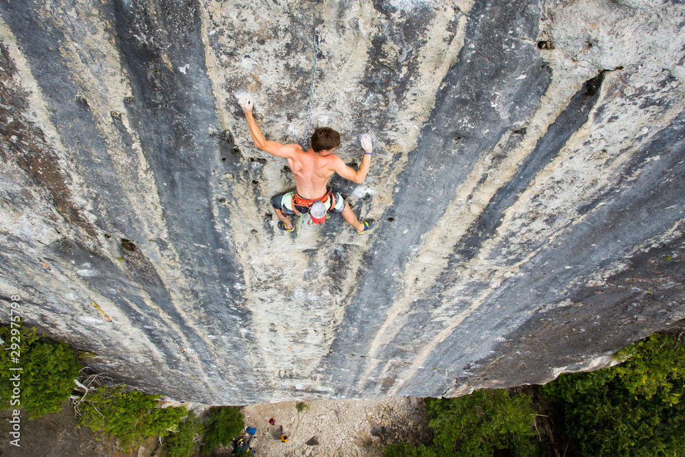 Strong shirtless rock climber on a tall striped wall, strong shoulders ...