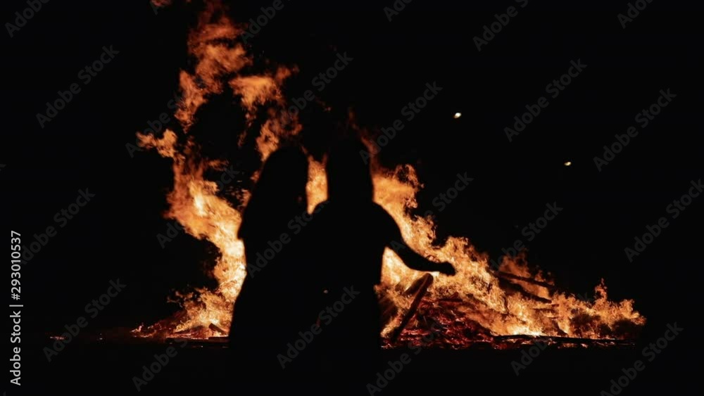 A large crowd of people celebrate an ethnic holiday by a giant bonfire ...