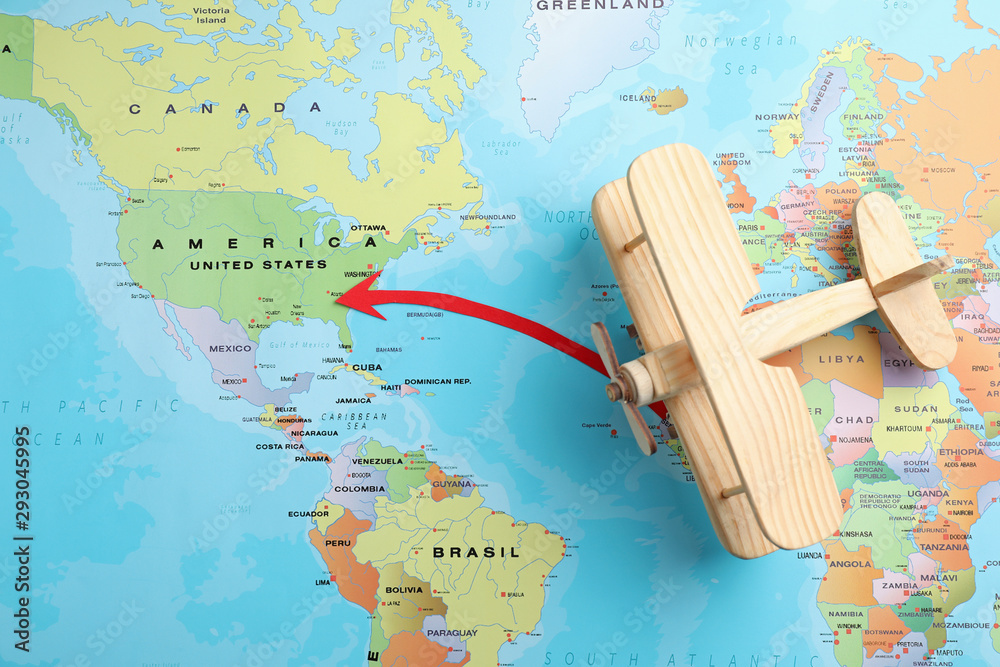 World map with wooden plane and red arrow pointing on USA, top view ...