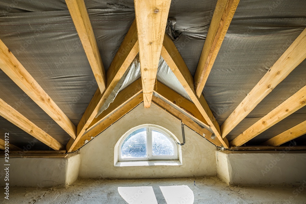 Attic of a building with wooden beams of a roof structure and a small ...