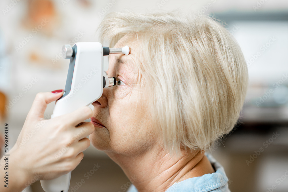 Doctor measuring the eye pressure with modern tonometer to a senior ...