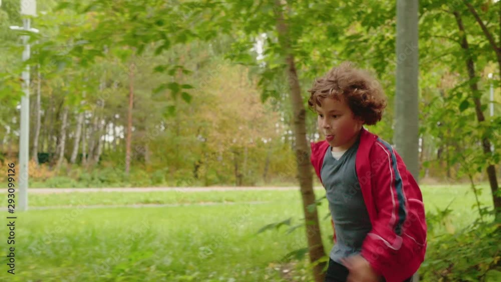 Young curly boy start running on pathway in summer park. Cheerful ...