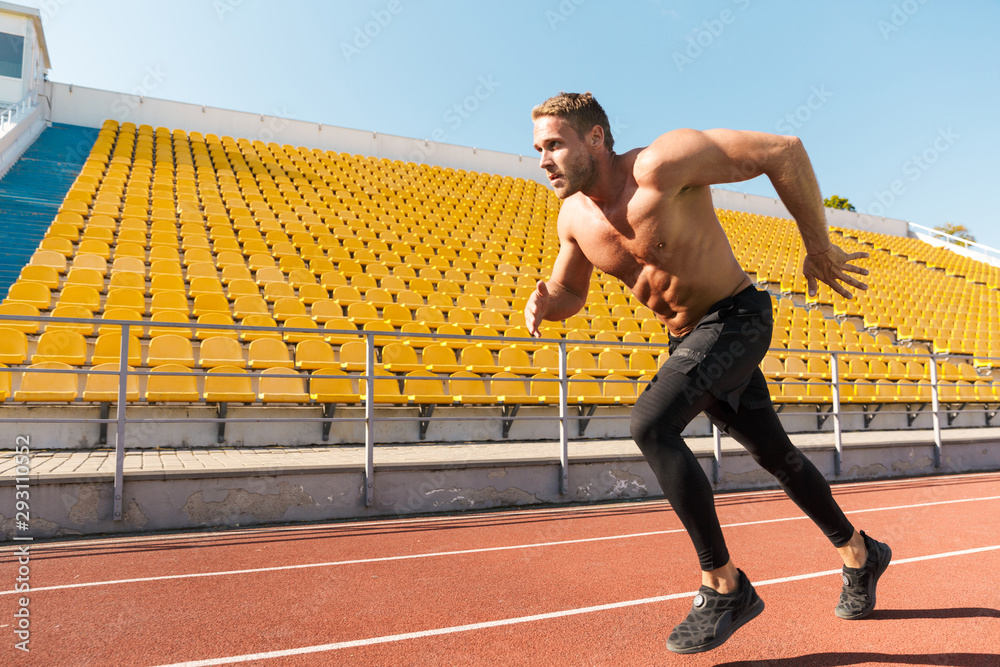 Image of shirtless sportsman running on track against stadium seats ...