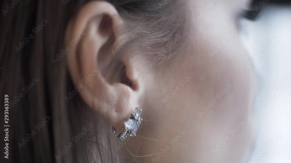 Close up of brunette woman hand pushing her hair back behind her ear ...