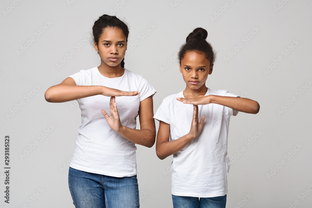 Two beautiful girls showing time out sign over grey background Stock ...