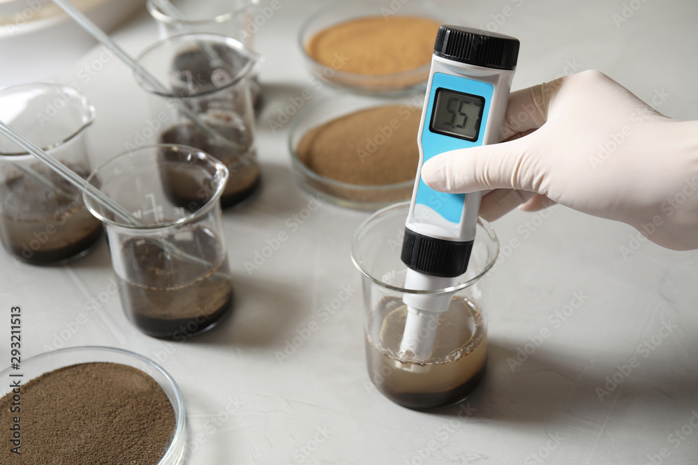 Scientist measuring acidity and pH of soil at table, closeup ...