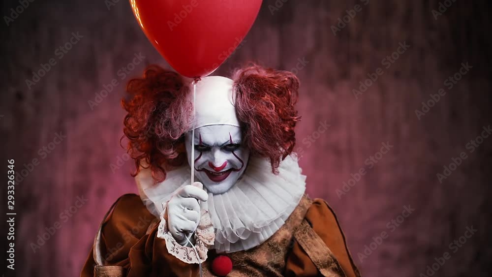 Vídeo do Stock: Creepy clown with colorful make-up is looking into the ...