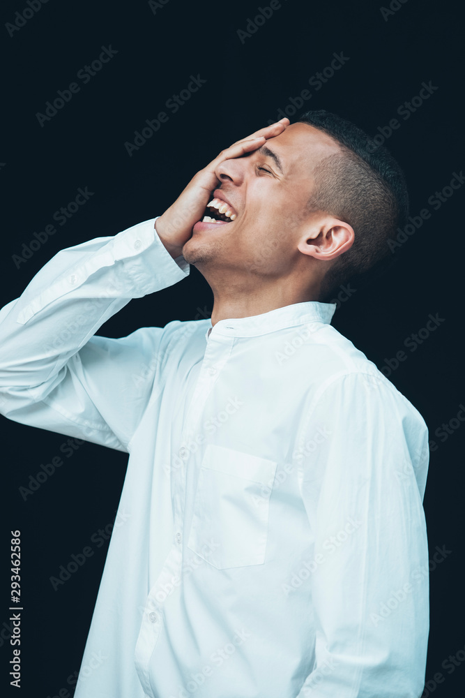 Laughing young woman with hand on his face wearing white shirt in front ...