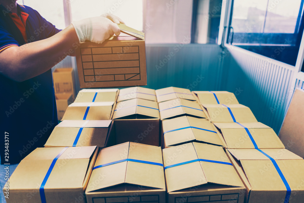 Man hand holding carton box puting box to the stack pallet in the ...