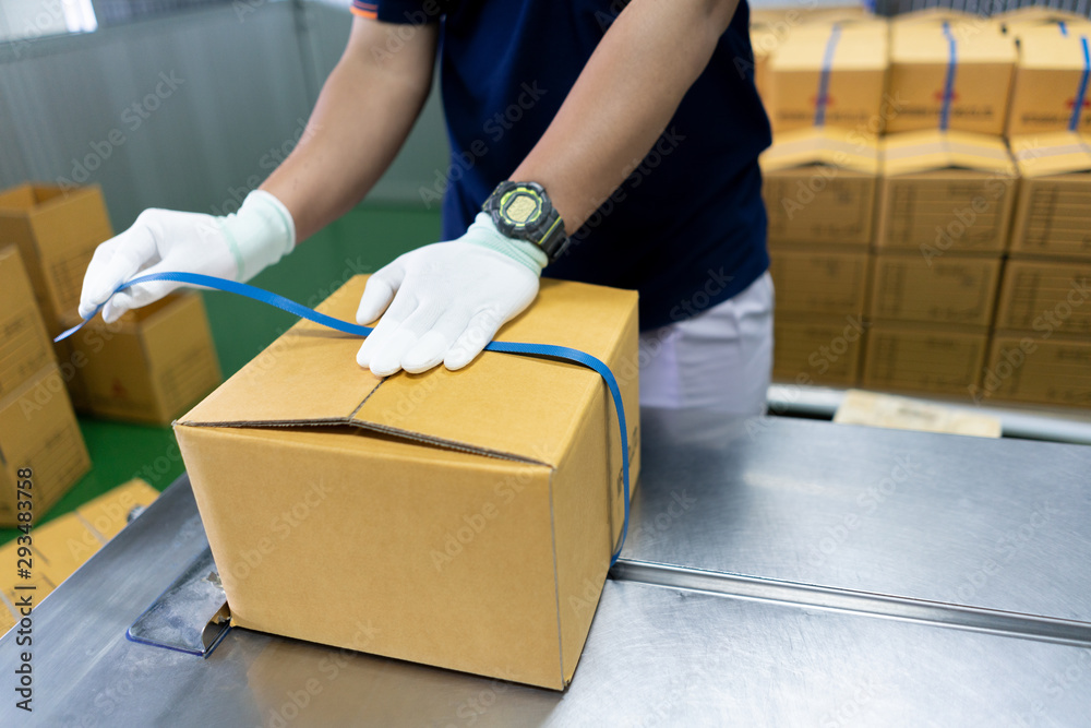 Foto de Man packing carton box by packing maching in the packing room ...