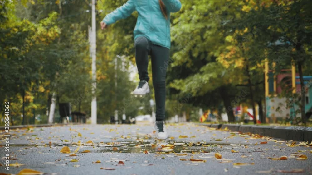 Girl play and jump in puddle in park after autumn rain. Fall rainy ...