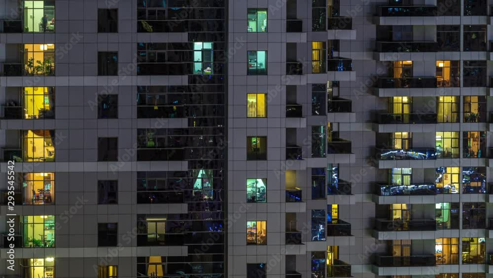 Rows of glowing windows with people in the interior of apartment ...