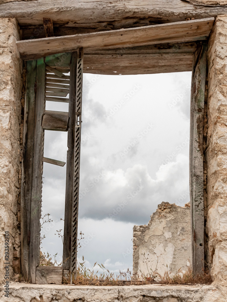 view through an old wooden window frame in a ruined house in the ...