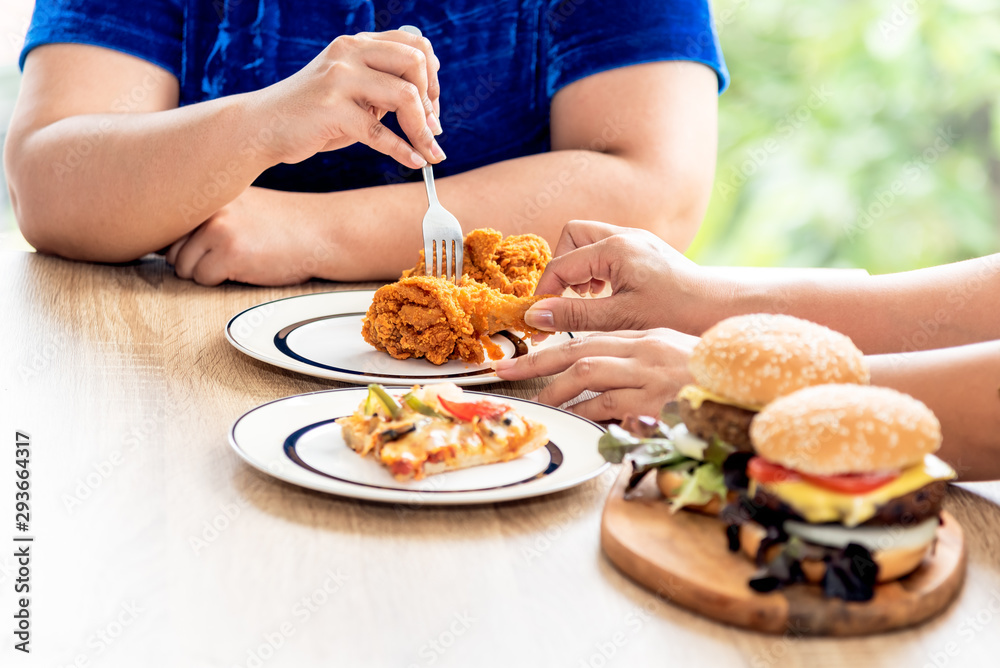 The fat woman sat down to eat together which had fried chicken, pizza ...
