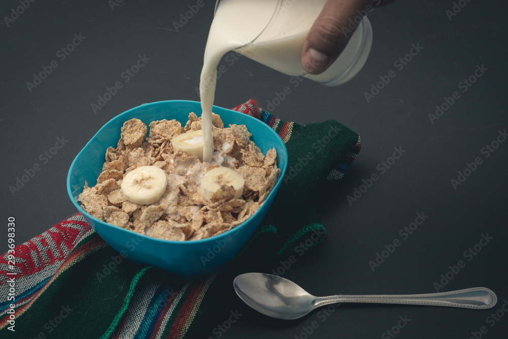 Cereal con leche y platano conbre mantel con una cuchara y un vaso con ...