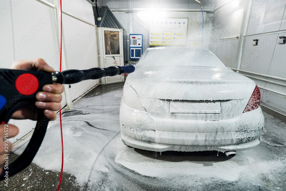 A man sprays foam on the car from a special spray. Car wash with foam ...