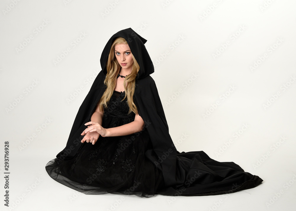 full length portrait of blonde girl wearing long black flowing cloak ...