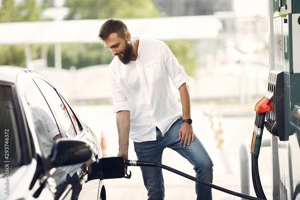 Man on a gas station. Guy refuelong a car. Male in a white shirt. Stock ...