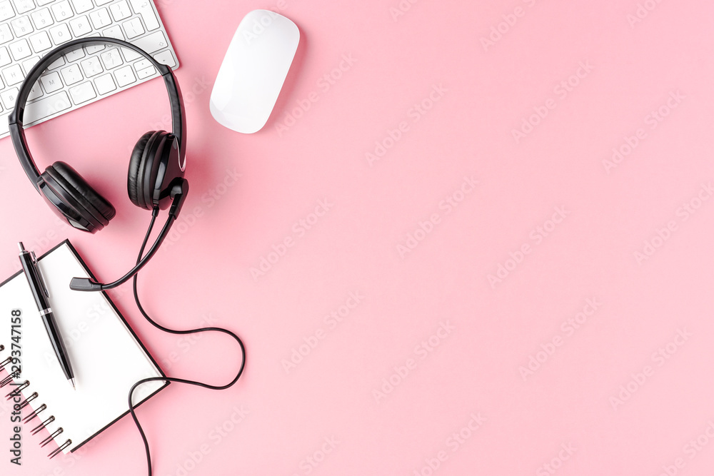 Call center desktop with headset and accessories on pink table. Top ...