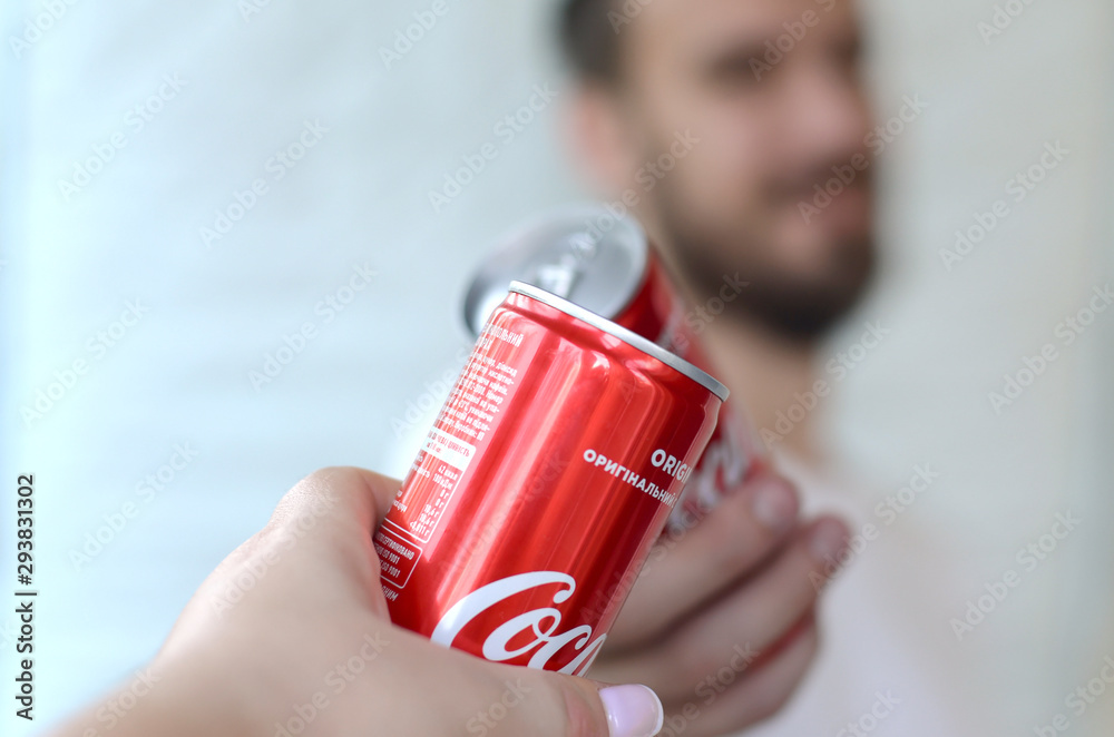 Happy young man raise Coca-Cola tin can with female friend in garage ...