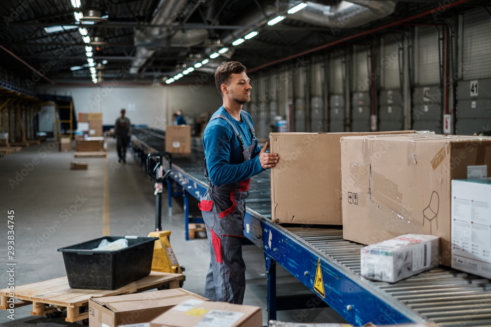 Warehouse worker working on a conveyor line Stock Photo | Adobe Stock